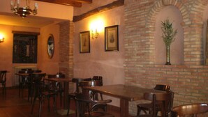 Interior de restaurante com paredes de tijolo, vigas de madeira e mesas e cadeiras.