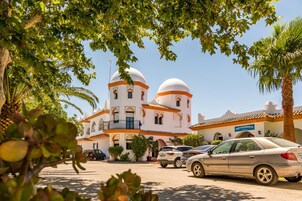 Um edifício com duas estruturas em forma de cúpula, um letreiro de restaurante e carros estacionados.