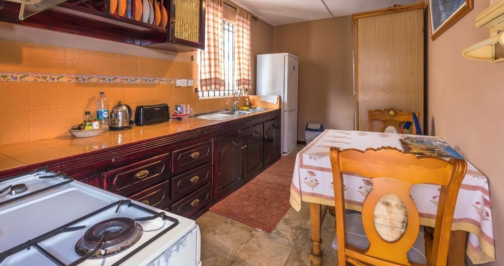 Cozinha compacta com fogão a gás, geladeira e área de refeições com mesa e cadeiras.