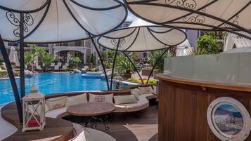 Área da piscina com mobiliário de exterior, guarda-sóis e vista para a piscina.