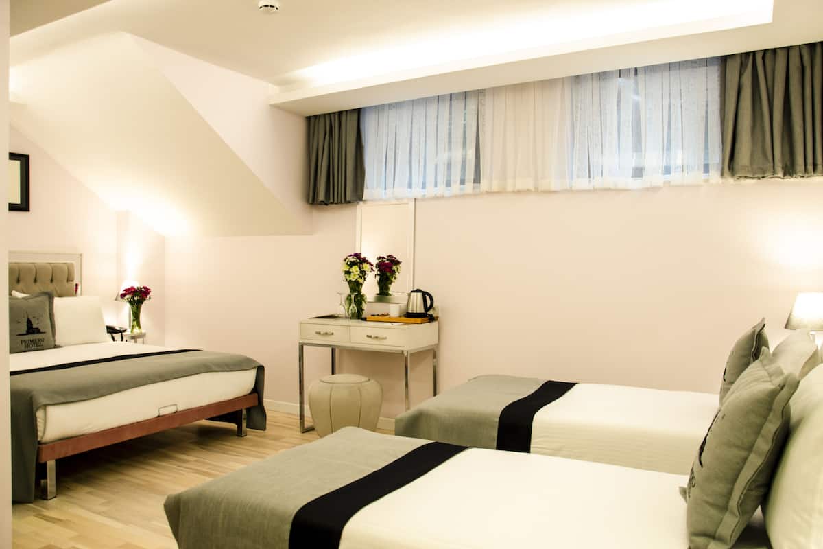 Quarto de hotel moderno com duas camas, uma escrivaninha e um espelho.