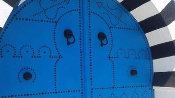 Uma porta azul com padrões elaborados e duas maçanetas circulares.