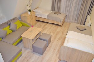 Quarto moderno e compacto com cama, dois sofás, uma mesinha e uma criadeira.
