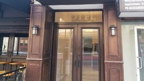 Entrada de um hotel com marquise escura e placa com a inscrição 'HOTEL'.