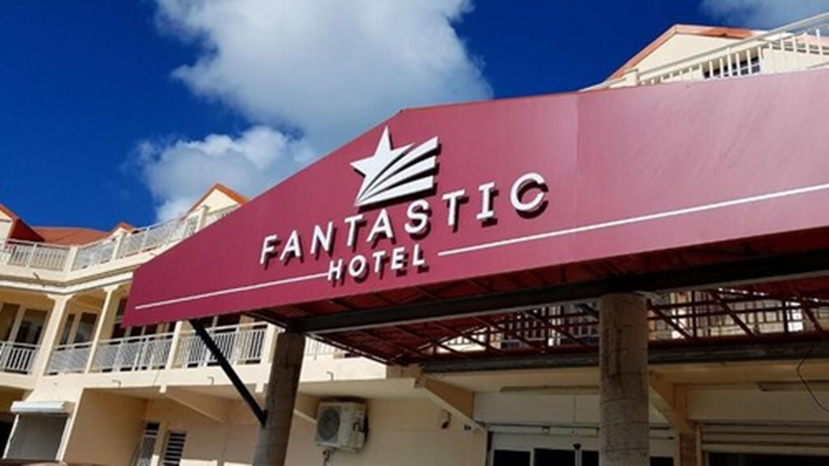 Um letreiro marrom com o texto 'FANTASTIC HOTEL' e um logotipo de estrela branca.