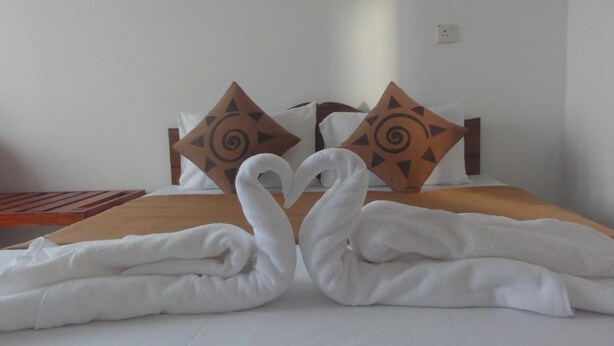 Quarto de hotel com cama, almofadas e toalhas dispostas em formato de coração.