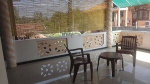 Varanda com duas cadeiras de madeira, piso de azulejos e painéis decorativos.