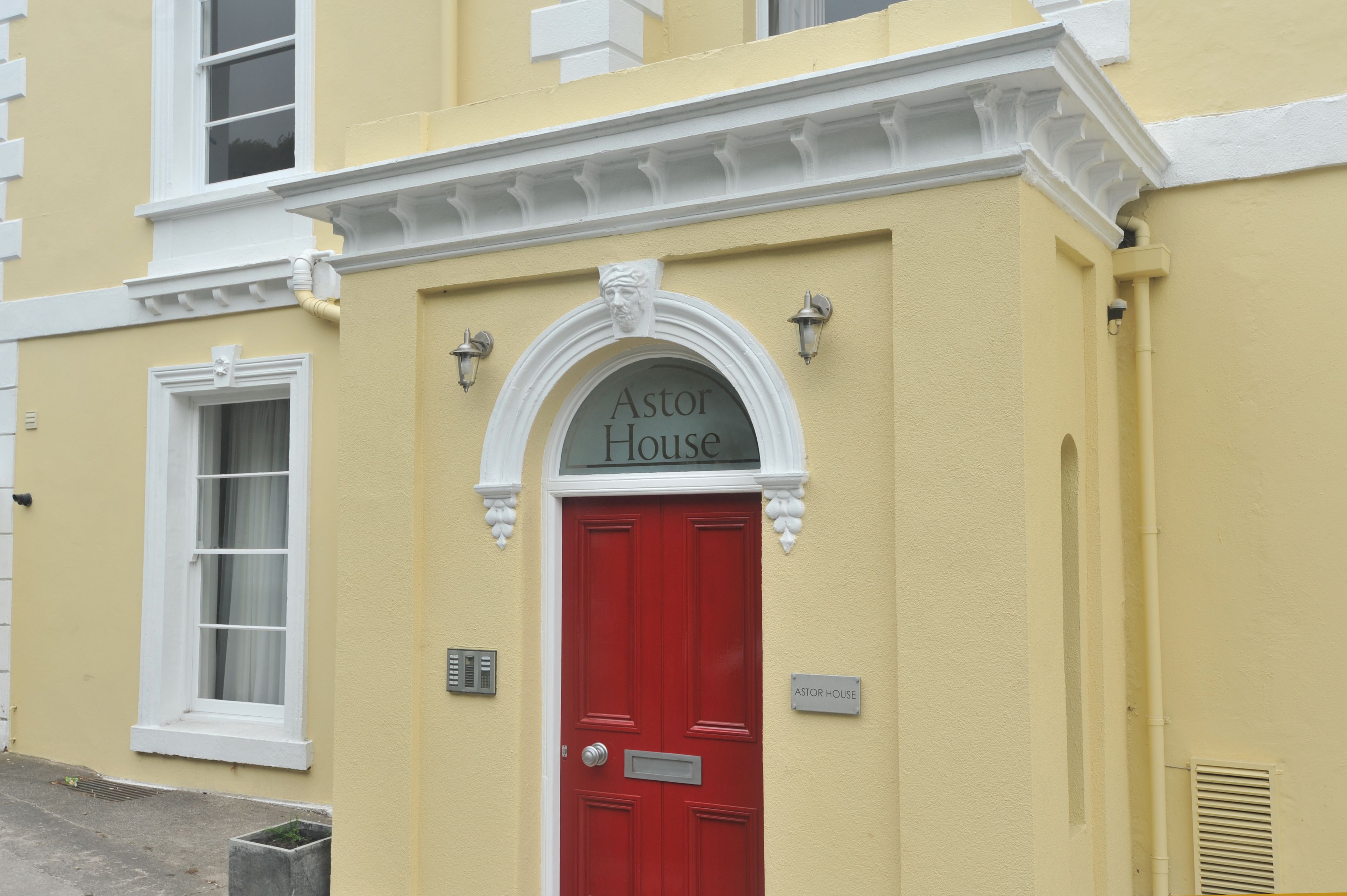 Um edifício com uma porta vermelha e uma placa que diz 'Astor House'.