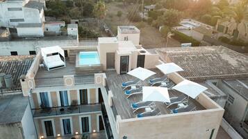 Terraço no telhado com piscina, espreguiçadeiras e guarda-sóis.