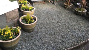 Um pátio de cascalho com plantas em vasos e um banco de madeira.