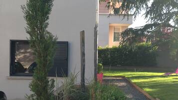 Um jardim residencial com uma pequena árvore, um poste de madeira e uma janela com um quadro.