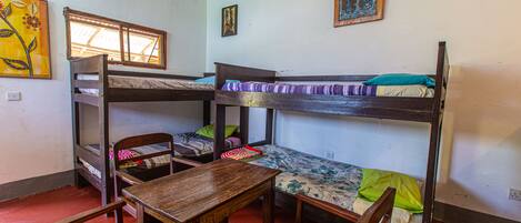 Um dormitório com beliches, uma mesa de madeira e cadeiras.