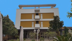 Um edifício moderno com fachada simétrica, grandes janelas e entrada central.