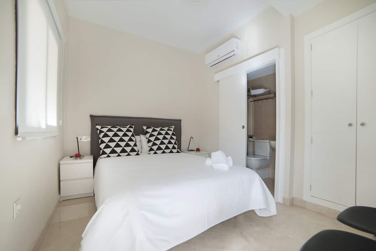 Quarto de hotel com cama, mesa de cabeceira, ar condicionado, armário e banheiro.