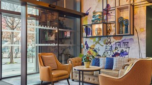 Um interior moderno com uma poltrona de couro, um sofá e uma pequena mesa. Há uma janela grande com vista para o exterior.