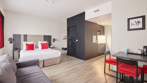 Quarto de hotel moderno com cama, sofá, escrivaninha e cadeira.