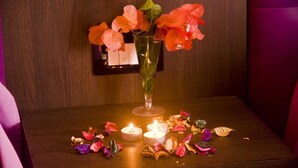 Uma mesa com um vaso de flores, velas e pétalas espalhadas.