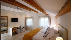 Quarto de hotel moderno com cama, escrivaninha e televisão.