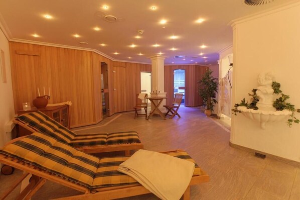 Um espaço de spa com painéis de madeira, uma mesa de massagem, uma mesinha com cadeiras e um objeto decorativo na parede.