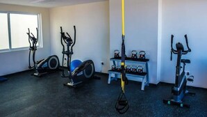 Uma academia com diversos equipamentos de ginástica, incluindo esteiras, bicicletas ergométricas e kettlebells.