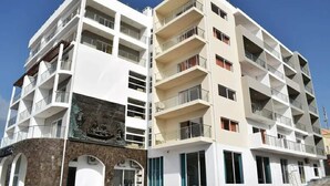 Um hotel com vários andares, varandas, fachada de pedra e céu claro.