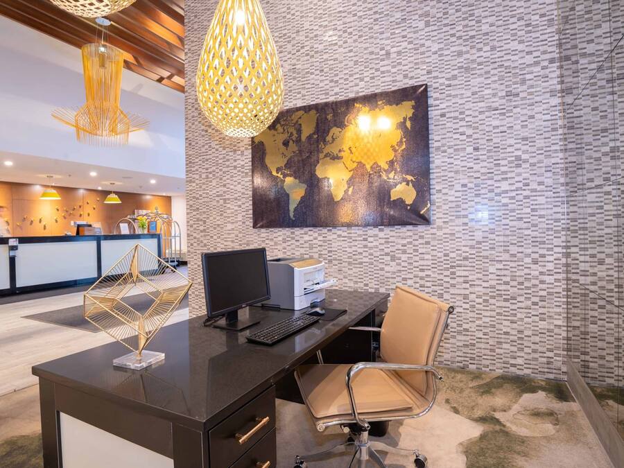Um espaço de escritório moderno com escrivaninha, cadeira, computador e objetos decorativos.