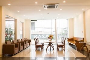 Um hall de hotel com balcão de recepção, área de estar e grandes janelas.