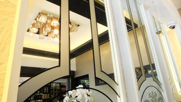 Um interior moderno com escada, um candelabro e um espelho decorativo.
