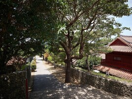 Uma trilha bordeada por árvores e um edifício tradicional com telhado em azulejos.