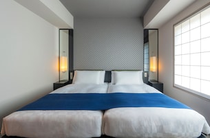 Quarto de hotel com uma cama grande, duas mesas de cabeceira e uma janela com vista.