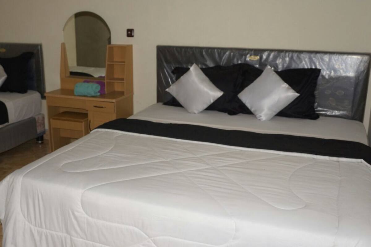 Quarto de hotel com duas camas, uma escrivaninha e um espelho.
