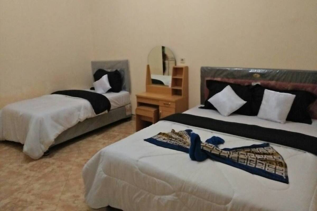 Quarto de hotel com duas camas de solteiro, uma secretária pequena e um espelho.