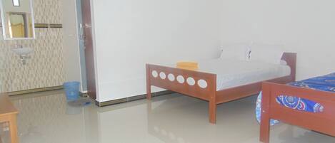 Quarto com cama de madeira, uma pequena mesa de cabeceira, um espelho e uma pia.