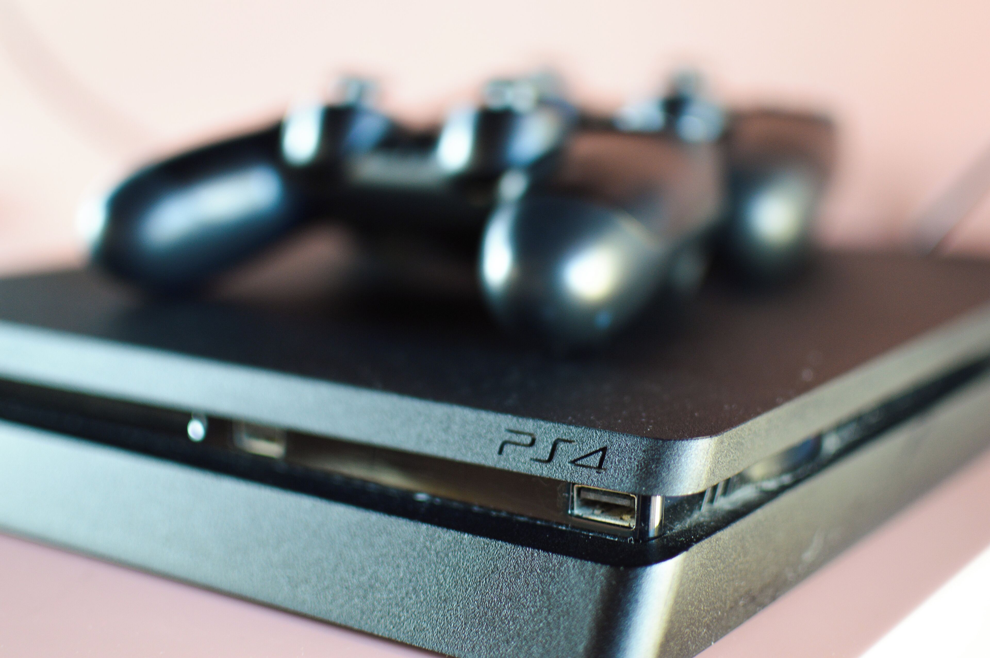 Um close-up de um console PlayStation 4 com controles por cima.