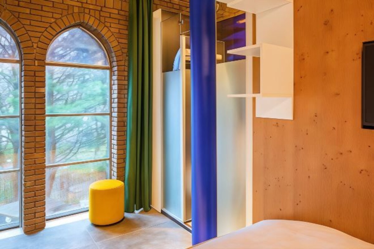 Quarto moderno com grandes janelas arqueadas, uma parede de madeira e uma parede azul de destaque.