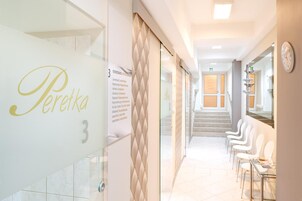 Corredor com área de recepção, quarto número 3 e sala de espera com cadeiras e balcão de atendimento.