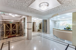 Um saguão de hotel com balcão de recepção, área de espera e elevador.