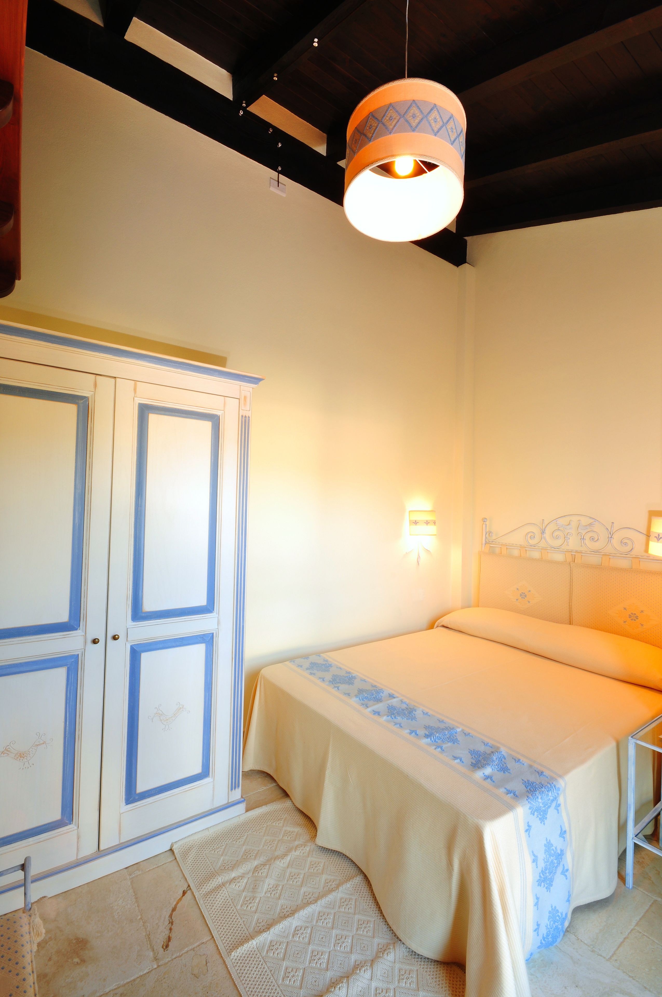 Quarto com cama, guarda-roupa e luminária suspensa.