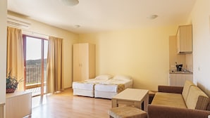 Um espaço compacto com cama, sofá, mesa pequena e cozinha compacta.