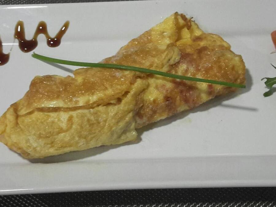 Um prato com omelete, tomate cereja e uma salada.