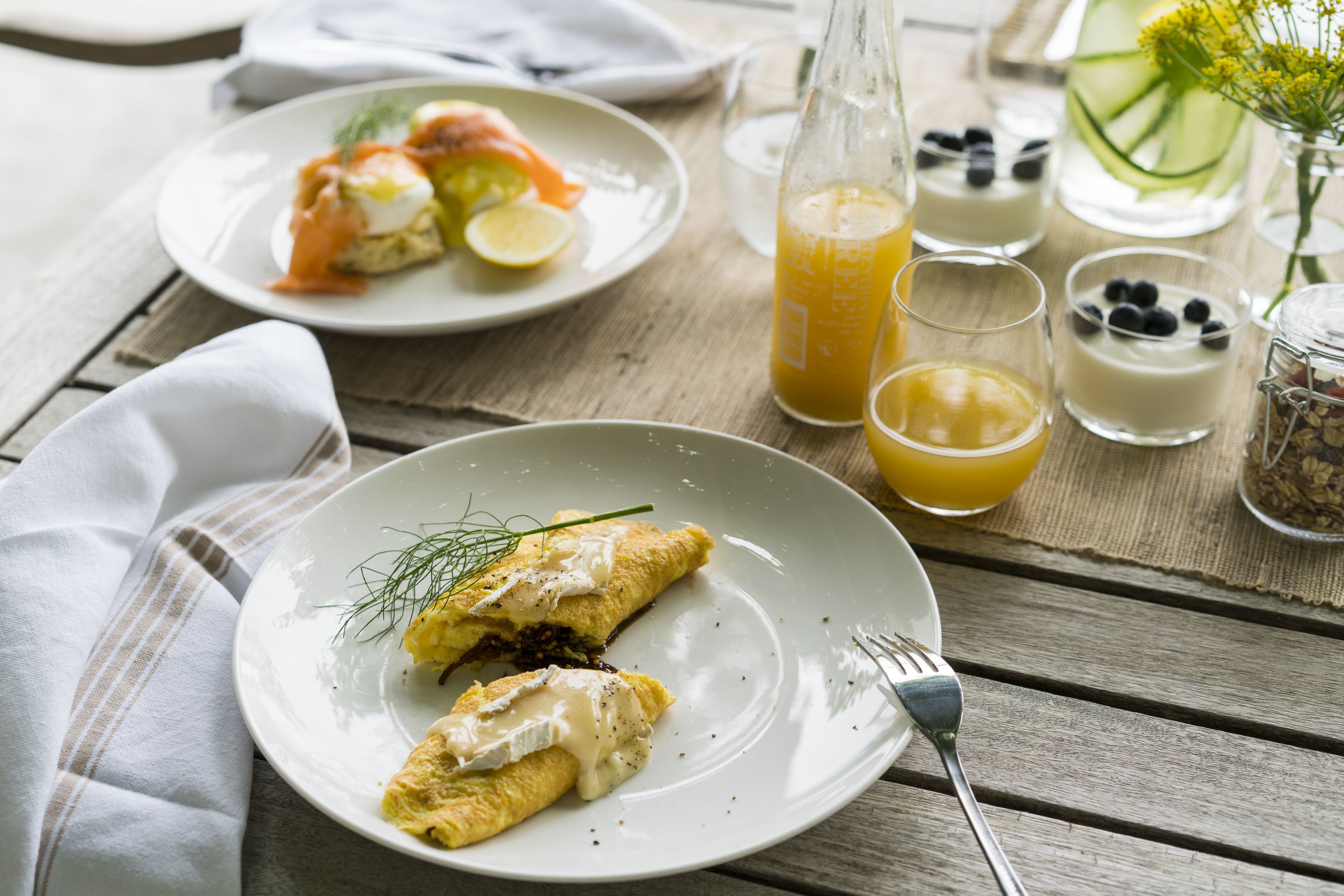Uma mesa de madeira com pratos de comida, uma garrafa de suco e copos.