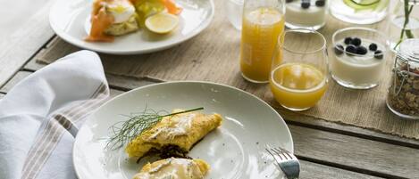 Uma mesa de madeira com pratos de comida, uma garrafa de suco e copos.
