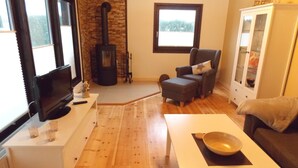 Uma sala de estar aconchegante com lareira, um sofá confortável, uma televisão e um espaço de jantar com mesa e cadeiras.