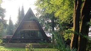 Estrutura triangular de madeira cercada por árvores e uma vedação.