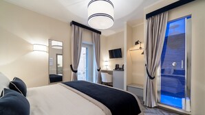 Quarto de hotel com uma cama grande, uma escrivaninha, chuveiro e televisão.