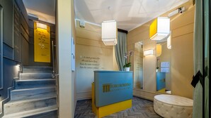 Uma área de recepção de hotel com escada, balcão de recepção, espelho e área de estar.