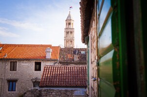 Vista de um edifício histórico com telhado em telhas e uma torre sineira.