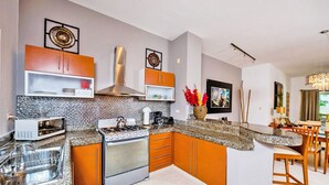 Uma cozinha moderna com bancadas de granito, eletrodomésticos de aço inoxidável e armários cor laranja.