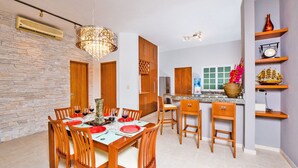 Cozinha moderna com armários de madeira, bancada de granito e área de refeições com mesa posta para quatro.