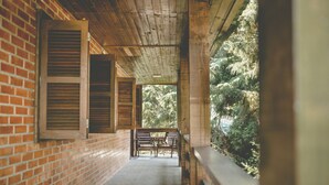 Um espaço ao ar livre coberto, com paredes de tijolo, persianas de madeira e um banco.